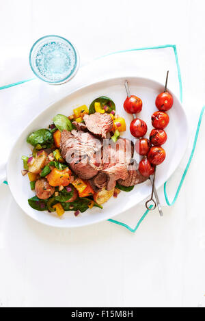 Grilled meat skewers on white plate with red tomato, chili peppers ...