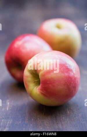 Three apples Malus domestica with red and yellow skin are stacked on a ...