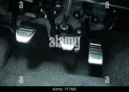 Closeup of gas clutch and brake pedals inside red sports racing car ...