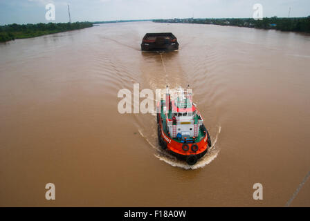 A tugboat is pulling an empty barge on Batanghari river in Muara Sabak ...