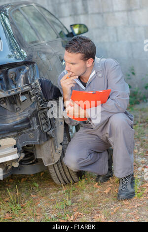 Mechanic with clipboard, assessing car Stock Photo - Alamy
