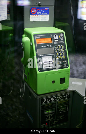 Old green Japanese public telephone in a cabinet at the side of the ...
