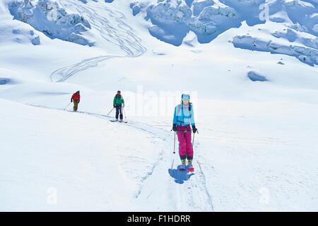 Row of male and female skiers skiing down snow covered ski slope, Aspen ...