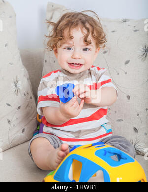 Adorable toddler playing with car toy sitting on table at kindergarten ...