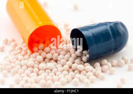 Blue Capsule with white drug balls inside isolated on blue. 3D ...