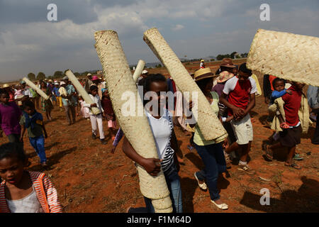 A procession to the tomb. Malagasy people holding mats which will cover ...