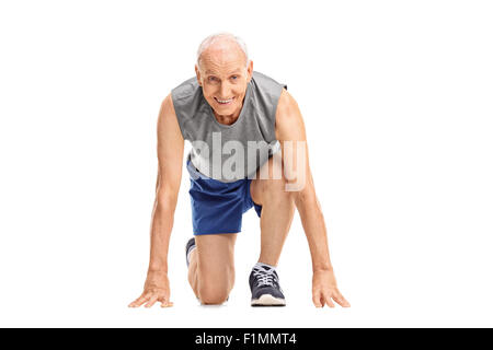 Athlete in starting stance on red track surface under bright sunlight ...