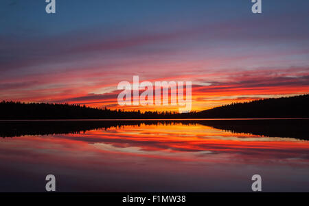 Colorful sunset over a calm lake with reflections in the water and ...