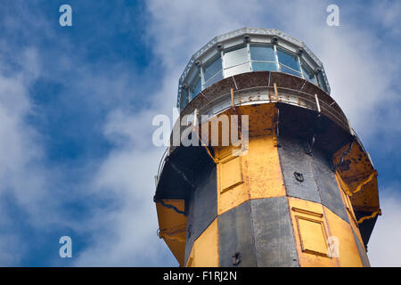 Top of a beacon with yellow lighthouse lamp in metal frame over blue ...
