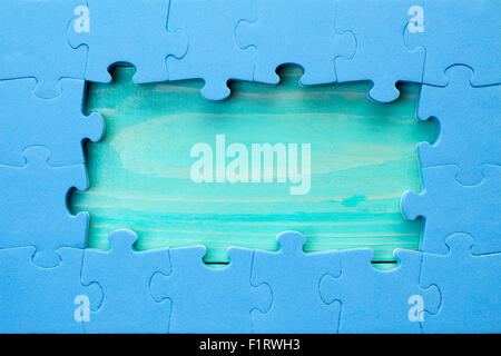 Puzzle pieces arranged as a border around a green wooden surface Stock ...