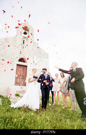 Guests throwing rose petals on bride and groom Stock Photo - Alamy