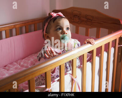 Baby girl with pacifier inside crib Stock Photo - Alamy