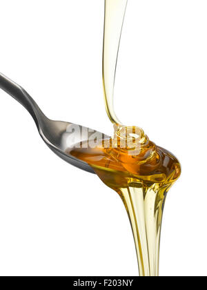 Golden treacle flowing onto a spoon isolated on a white background ...