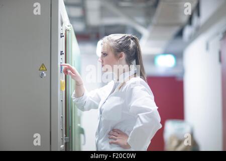 Young female scientist pressing button on machine control panel in ...