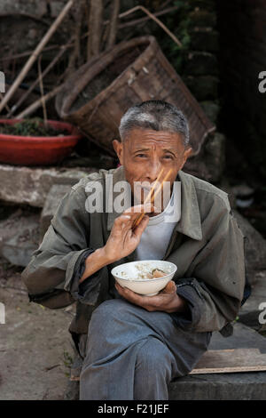 Smiling senior man eating rice and smiling young woman eating pizza ...