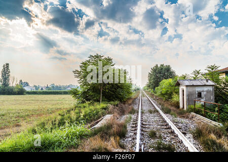 Rails of a country railroad crossing under a cloudy sky in Summer in ...