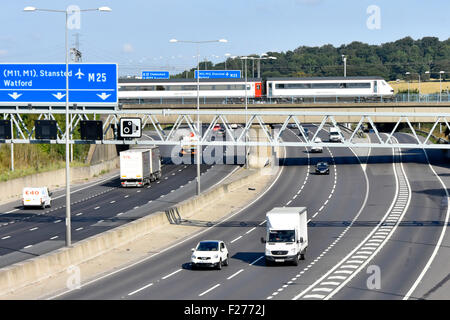 M25 motorway signs & railway bridge with Greater Anglia passenger train ...