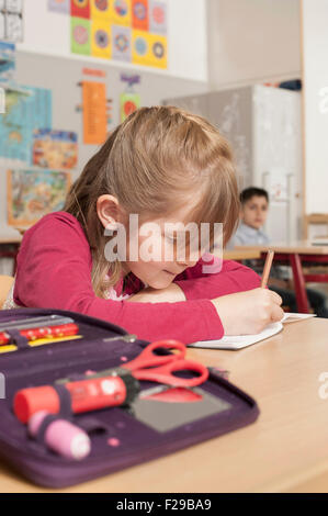 Two pupils writing in notebook at desk in classroom Stock Photo - Alamy
