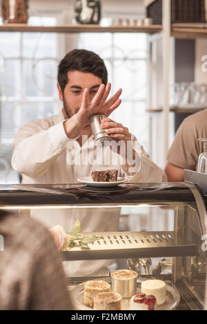 Young man sprinkling icing sugar on stack of waffles, close-up Stock ...