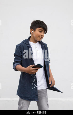 Asian kid 10 years enjoying listening music from mobile phone wear ...