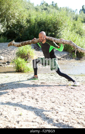Man doing CrossFit exercise with tree trunk Stock Photo - Alamy