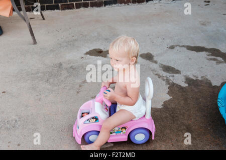 Toddler baby plays with toy cars on a studio yellow background. Happy ...