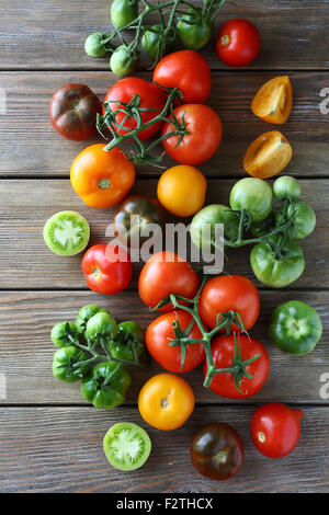 Assorted ripe tomatoes on a wooden stand. Fresh red and orange organic ...
