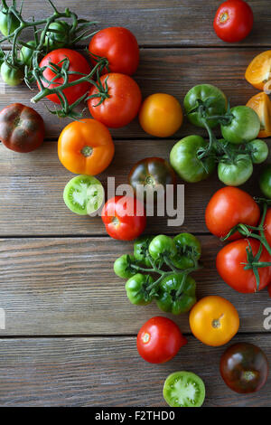 Assorted ripe tomatoes on a wooden stand. Fresh red and orange organic ...