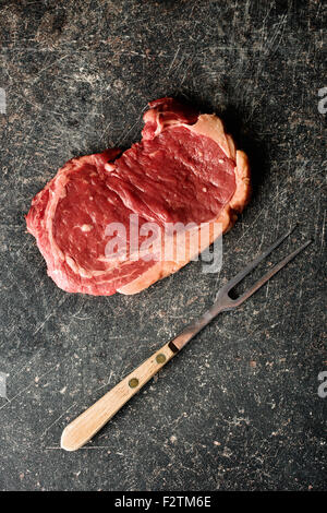 Rib eye raw fillet with fork and knife,salt and pepper with rosemary on ...
