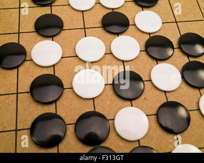 black and white stones on a ‘GO’ board made from wood on white ...