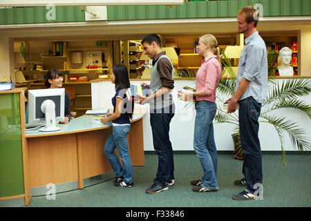 Students in a row at the library counter Stock Photo - Alamy
