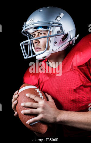 Determined American football player in uniform holding ball Stock Photo ...