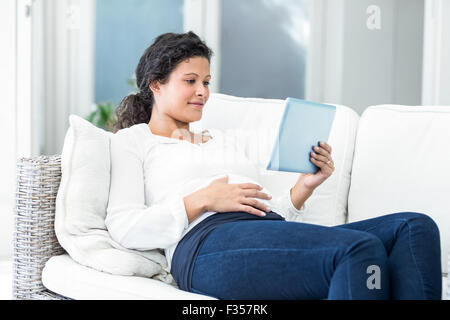 Woman using tablet computer while reclining on sofa in office Stock ...
