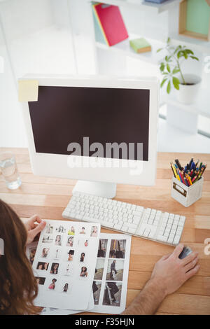 Hipster holding photographs at computer desk Stock Photo - Alamy