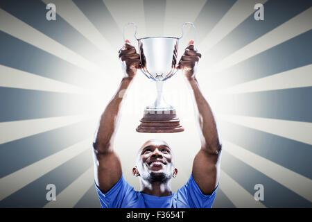 Composite image of happy sportsman looking up while holding trophy ...