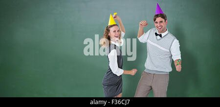 Composite image of geeky couple dancing with party hat Stock Photo - Alamy