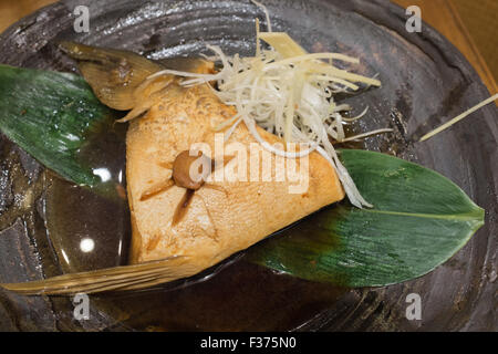 Hamachi cooked in sauce on black ceramic plate Stock Photo - Alamy