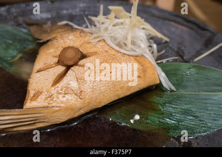 Hamachi cooked in sauce on black ceramic plate Stock Photo - Alamy