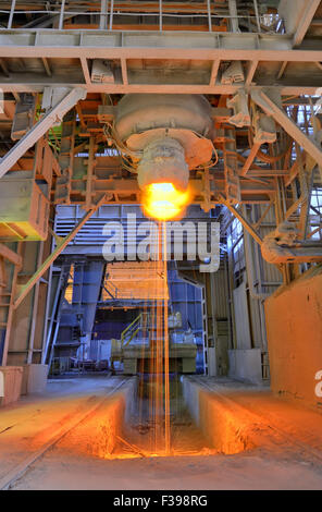 Liquid iron molten metal pouring from ladle container into mold ...
