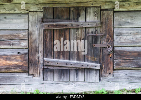 An old wooden log door is closed, locked and latched with a log beam ...