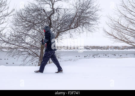 a man with a cold bundled up in a coat, knit cap, gloves and scarf ...