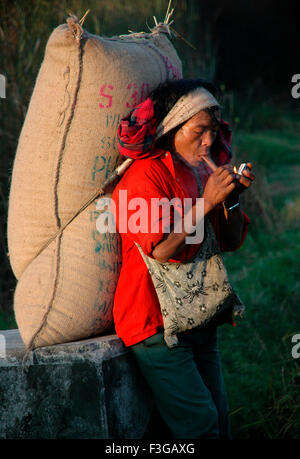 Rural woman smoking cigarette wearing silver jewellery bangles necklace ...