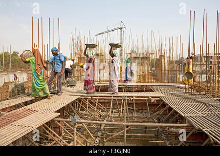 Women construction workers carrying concrete mixture on their head ...
