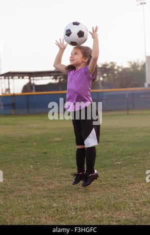 Girl heading football on practice pitch Stock Photo - Alamy