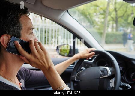 Woman talking on smartphone while driving modern car, view through ...