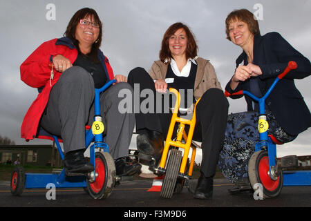 Three (3) women teachers having fun riding childrens small cycles at ...