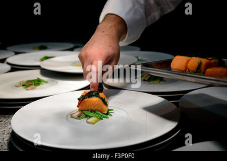 European professional chef plating up pasta before serving it to the ...