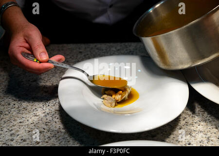 Gourmet chef plating up a dish of food in an Asian restaurant carefully ...