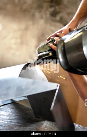 Metal working. Metalworker using an angle grinder in an engineering ...
