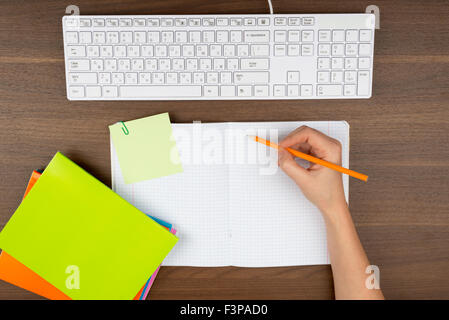 Humans hand writing in copy book with calculator Stock Photo - Alamy
